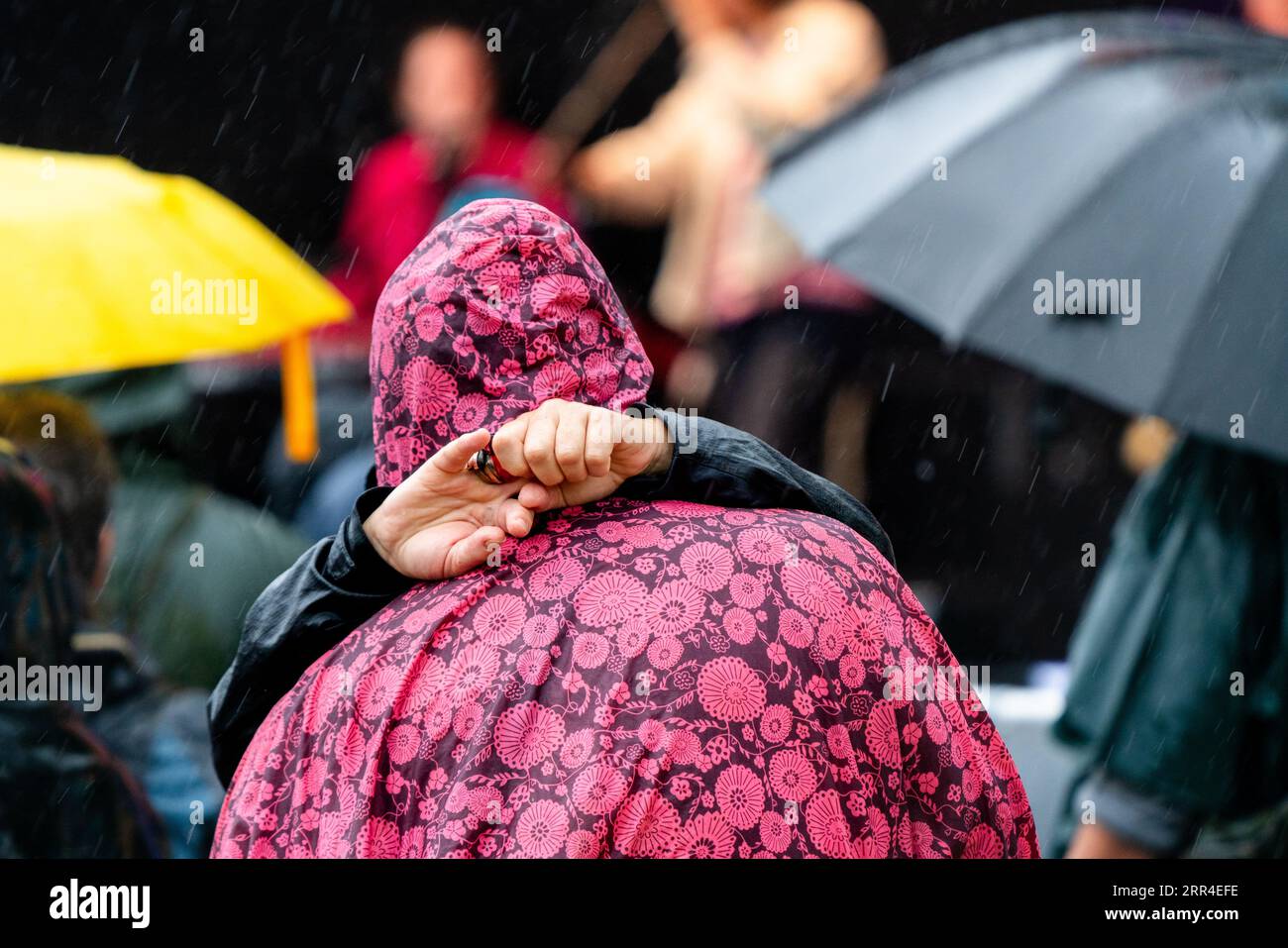 A faceless romantic couple dancing in rain clothes in the rain. Green ...