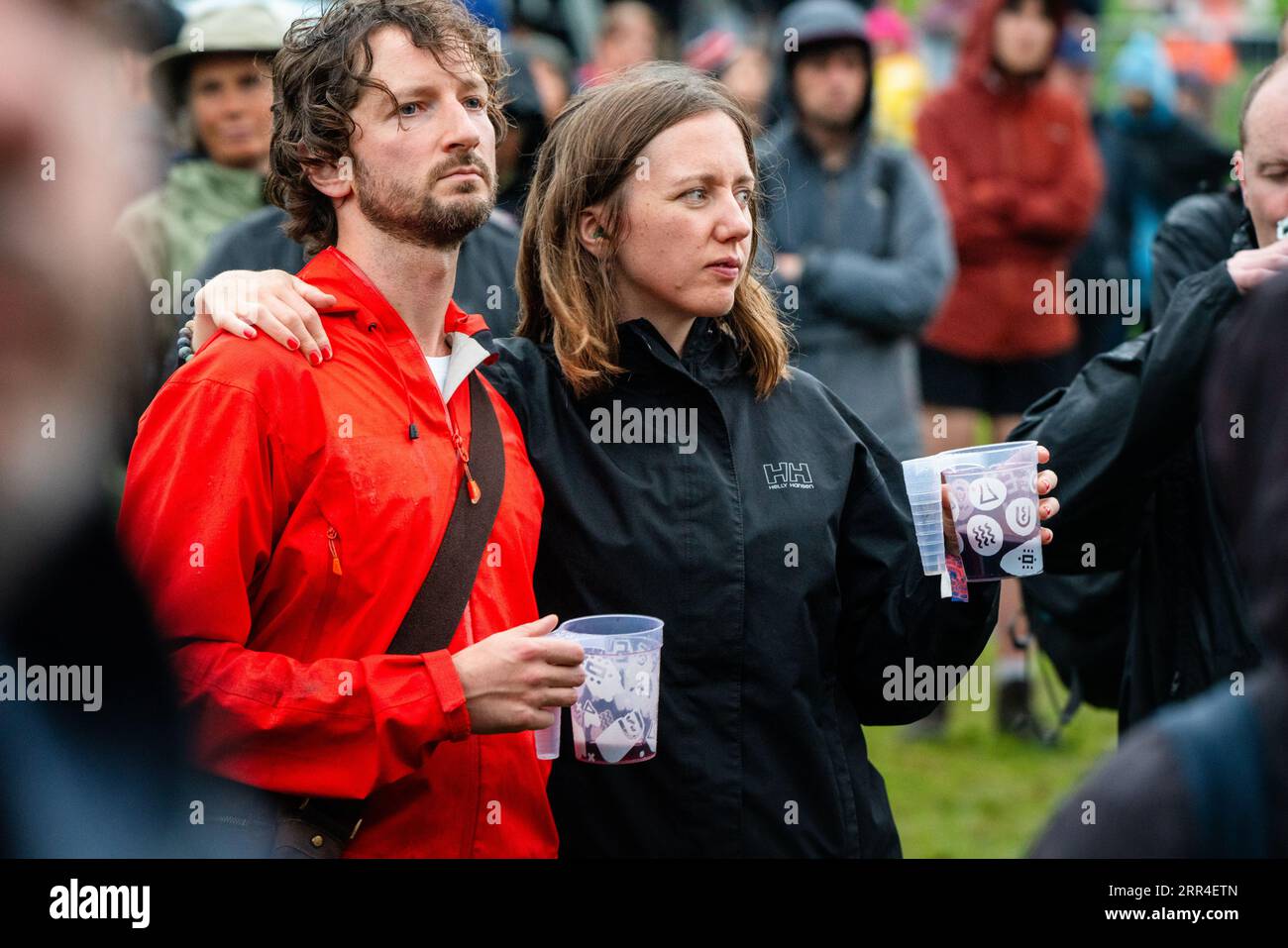 A couple looking grumpy with beers in wets in the rainstorn rain and ...