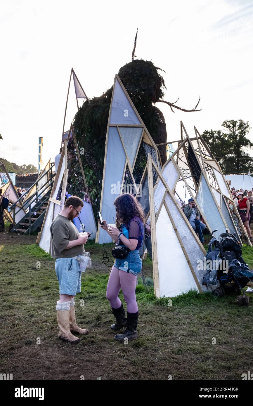 A couple scrolling on their mobile phones at the Wicker Man at Green ... A couple scrolling on their mobile phones at the Wicker Man at Green ...
