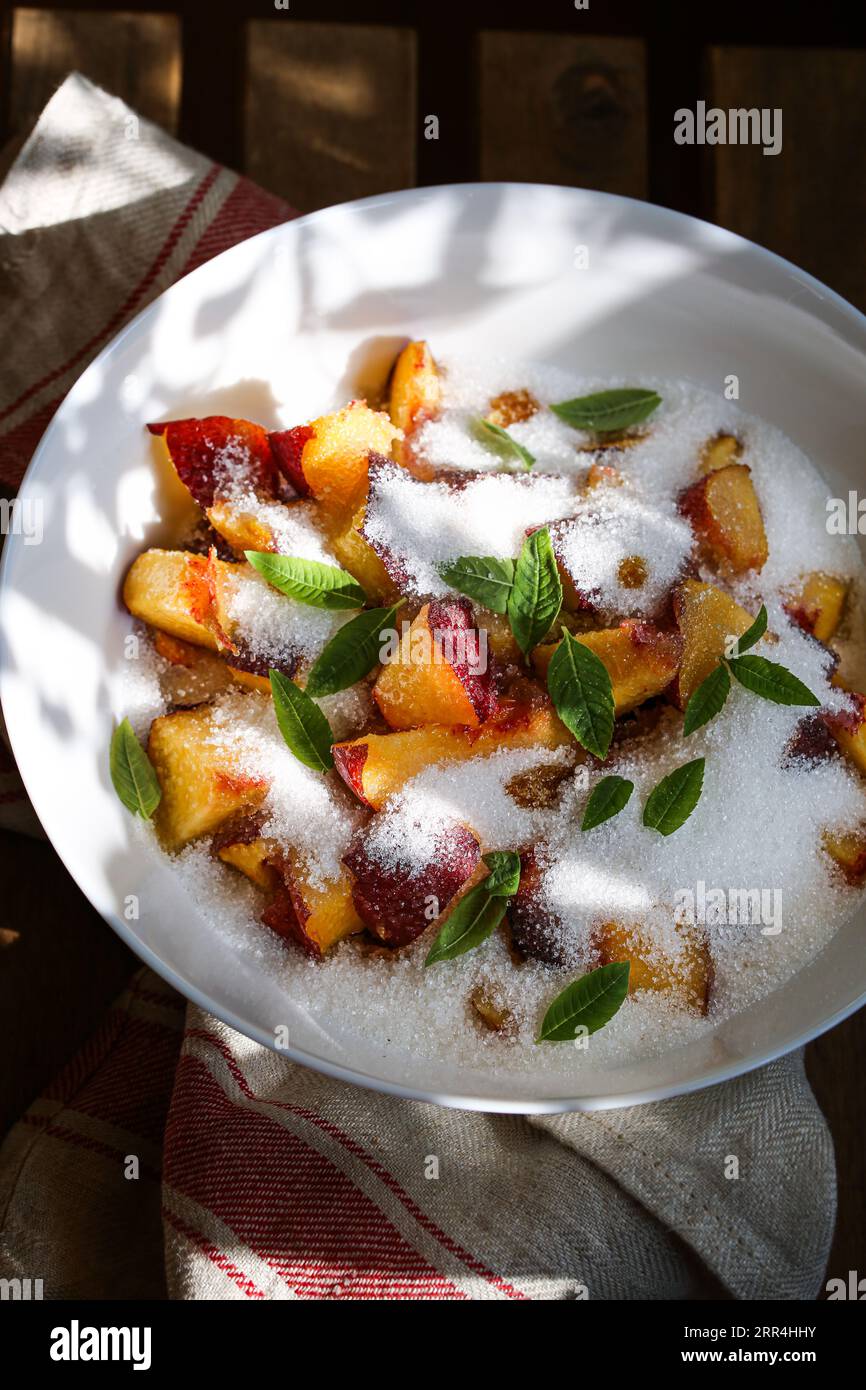 Diced peaches with sugar and lemon verbena leaves. preparation for jam ...