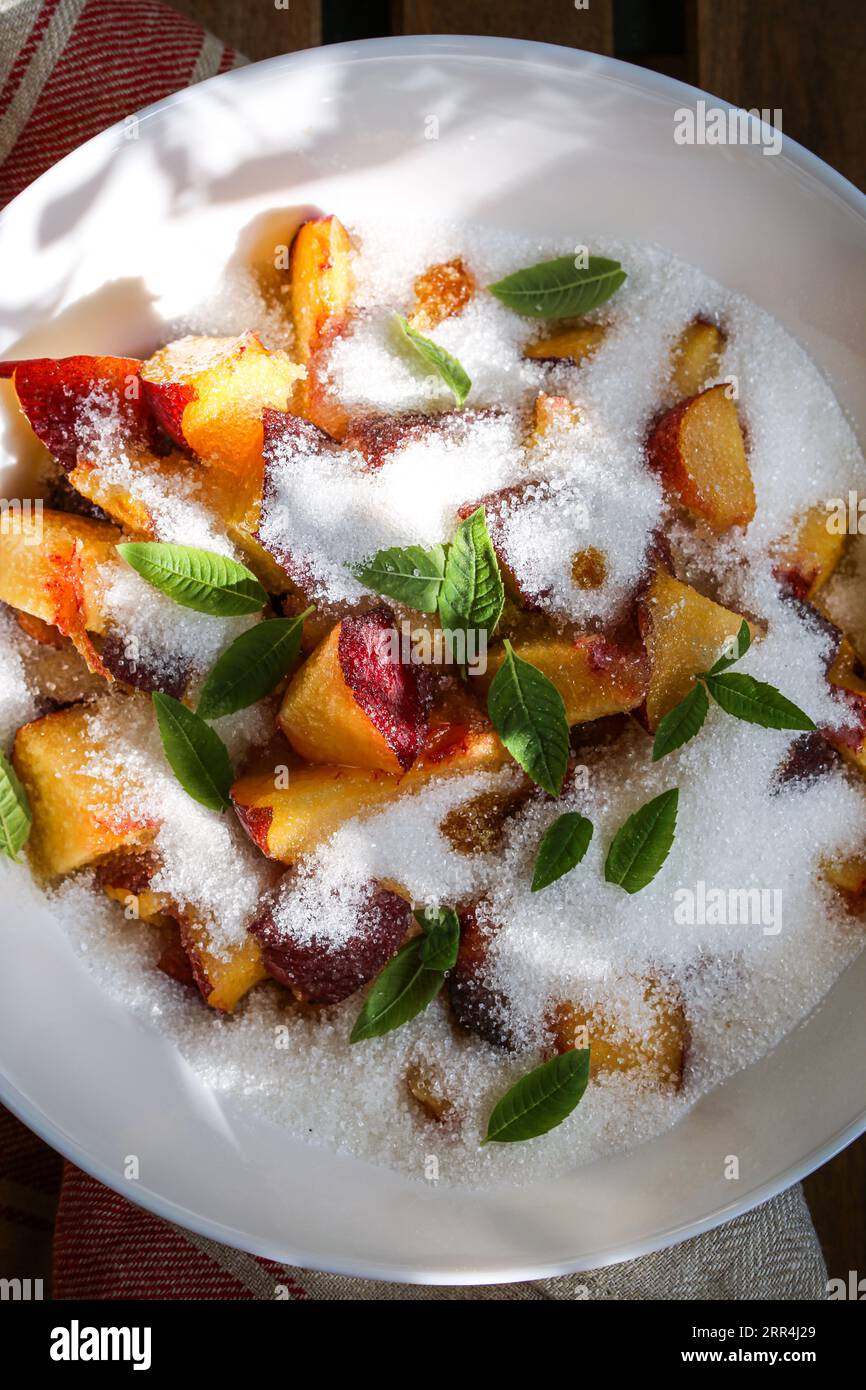 Diced peaches with sugar and lemon verbena leaves. preparation for jam ...