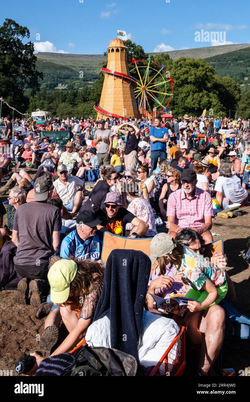 People sit in the mud in sunshine in the bar area outside the Far Out ...