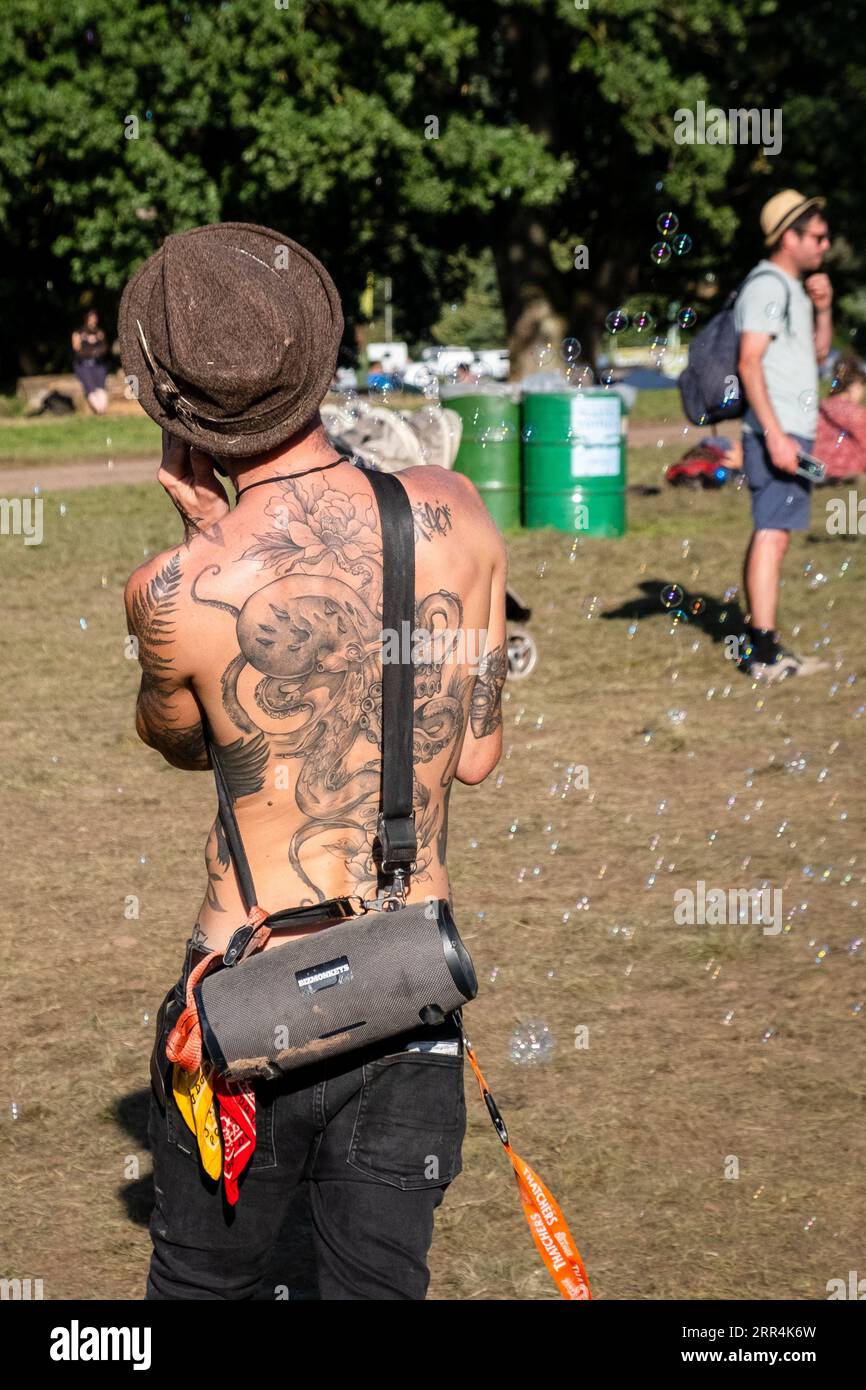 A man with a beatbox, full back tattoo and soap bubble gun at Green Man ...