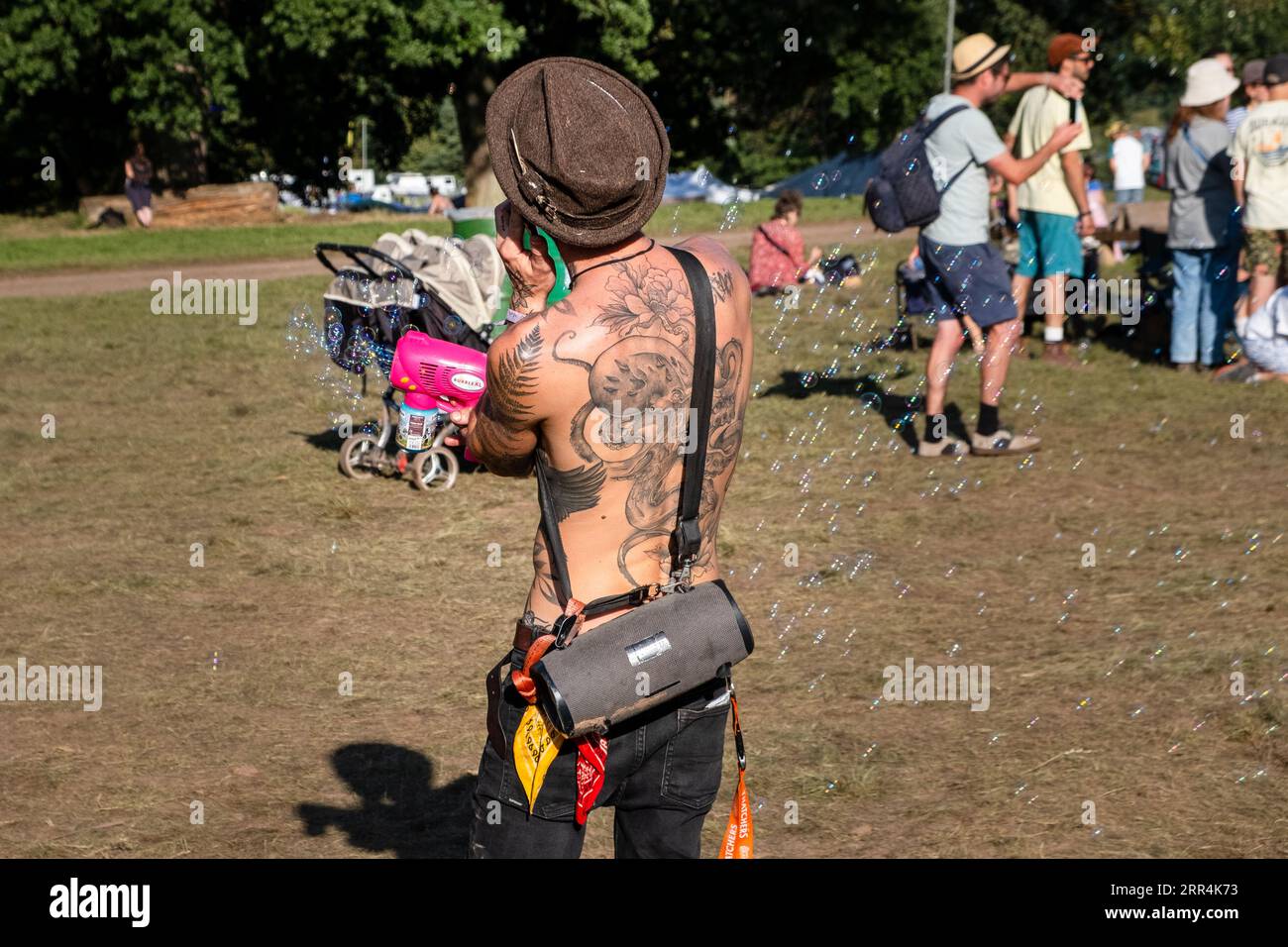 A man with a beatbox, full back tattoo and soap bubble gun at Green Man ...