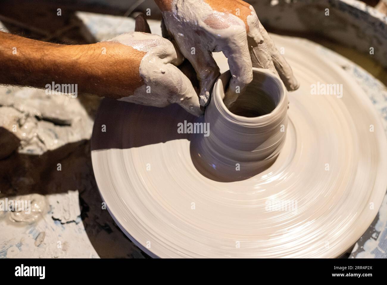 Closeup of the male hands doing pottery using clay on a potter's wheel ...