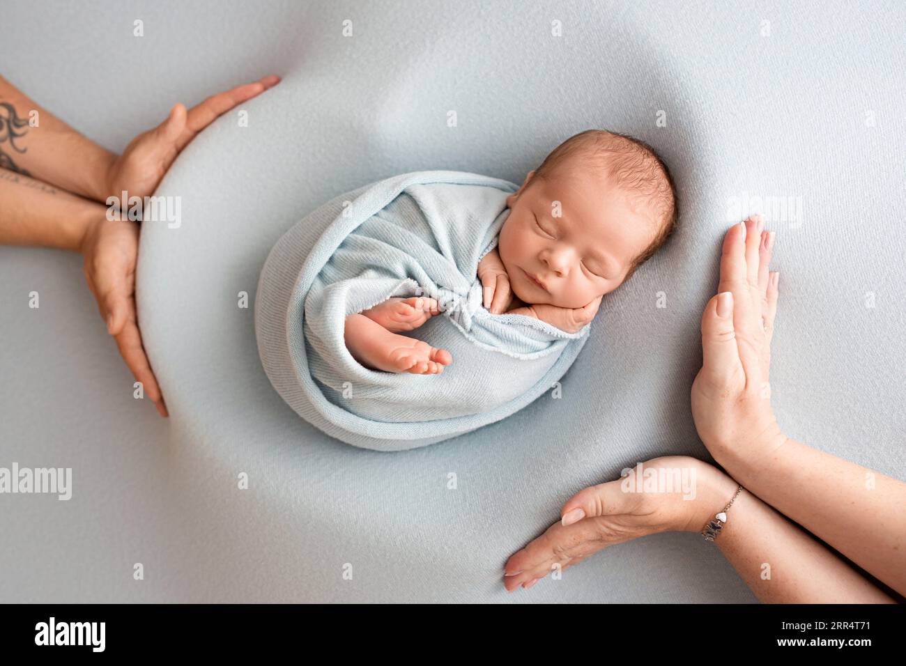 A cute newborn boy in the first days of life sleeps in a delicate blue ...