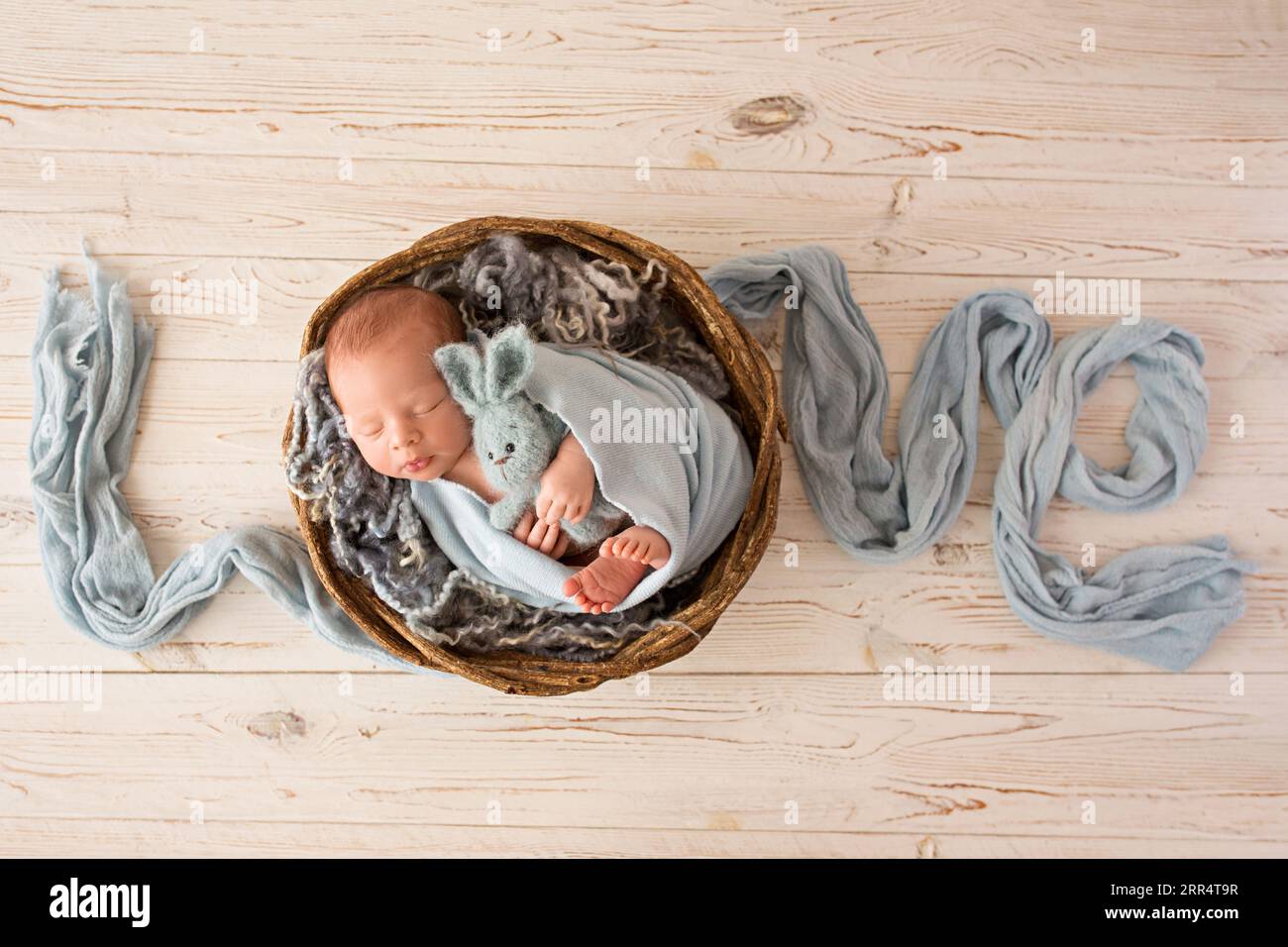 A cute newborn boy in the first days of life sleeps in a blue winding ...