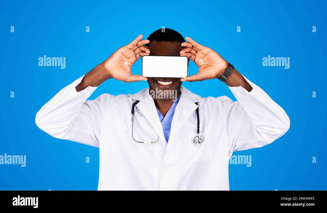 Happy young african american guy doctor in white coat puts phone to ...