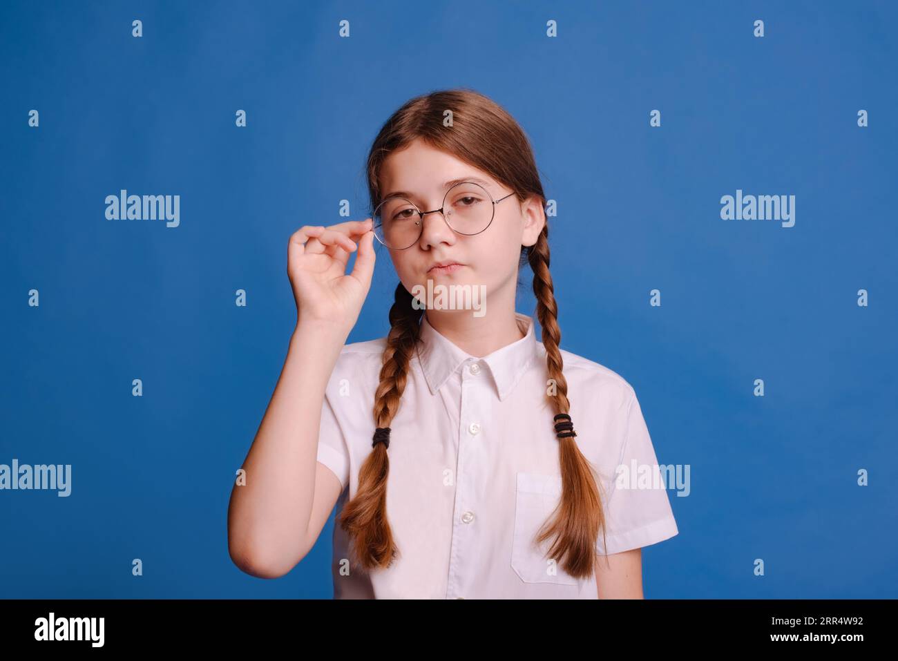 serious schoolgirl in round glasses for vision correction looking at ...