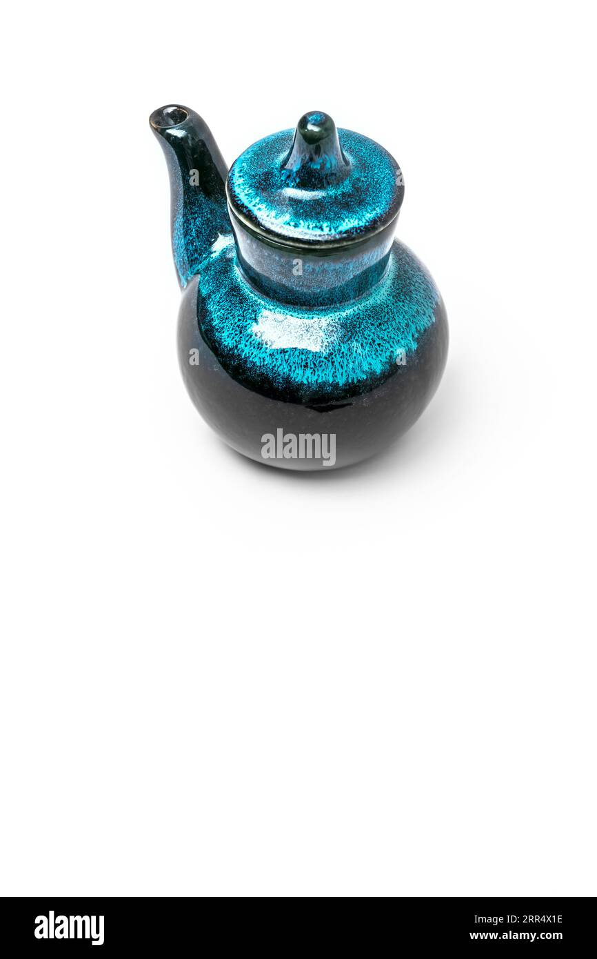 A small shiny blue and black porcelain jug on a smooth white surface ...