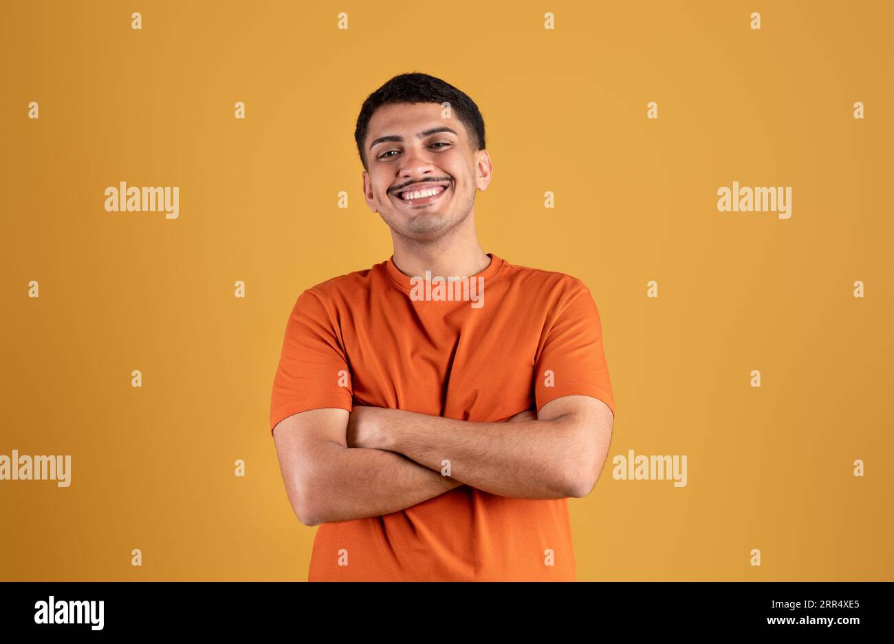 Portrait of happy confident brazilian man standing with folded arms and ...