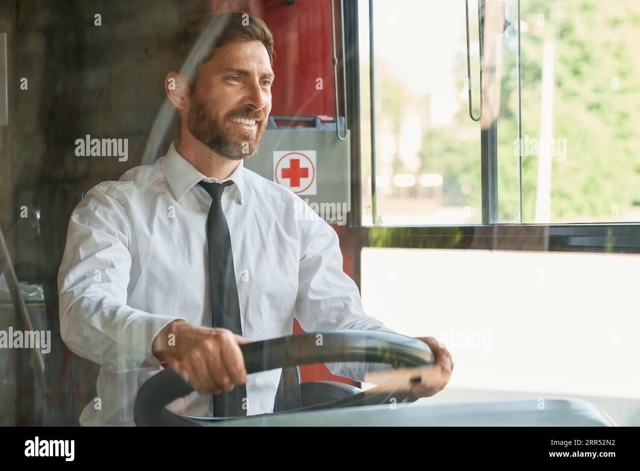 Cheerful male driver looking ahead, while driving public transport at ...