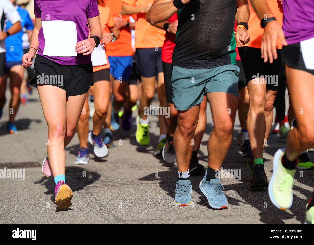 legs of male and female runners with sneakers running during city ...