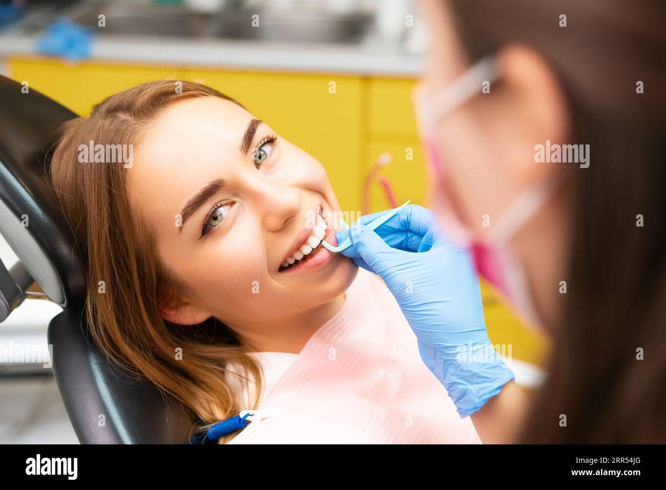 A dentist instructs a young woman on the correct technique for using ...