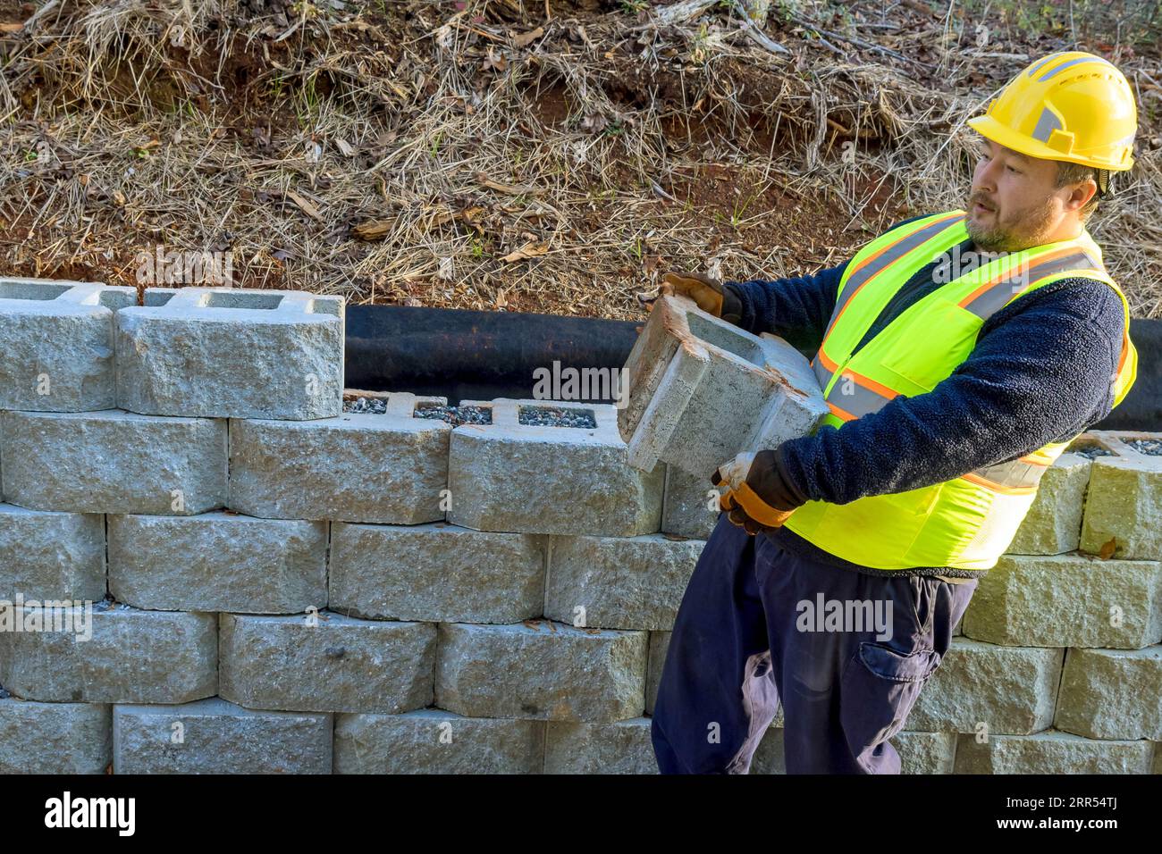 Construction worker lifted concrete block before mounting it on ...