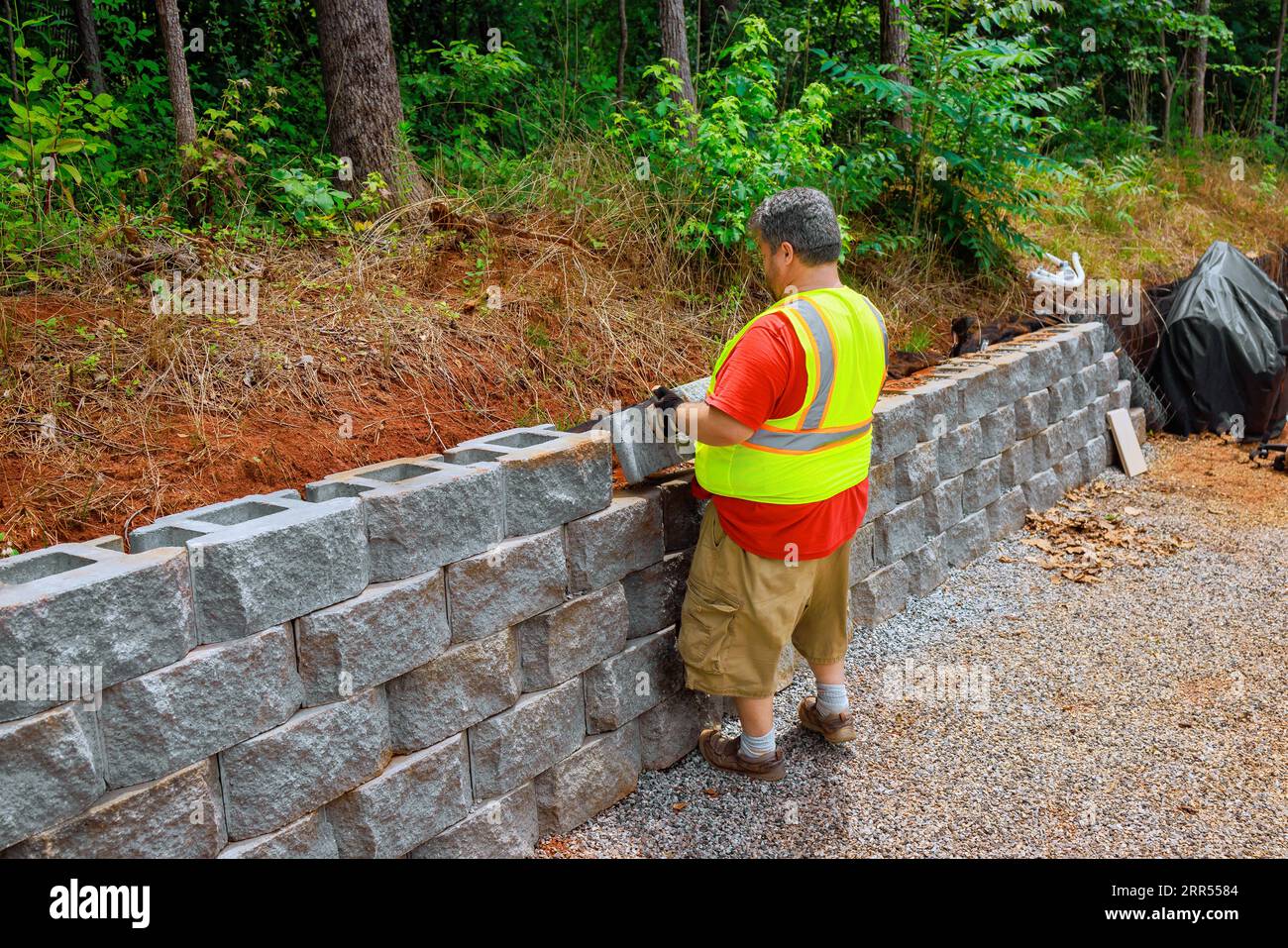 Construction worker mounted concrete blocks to retaining wall on ...