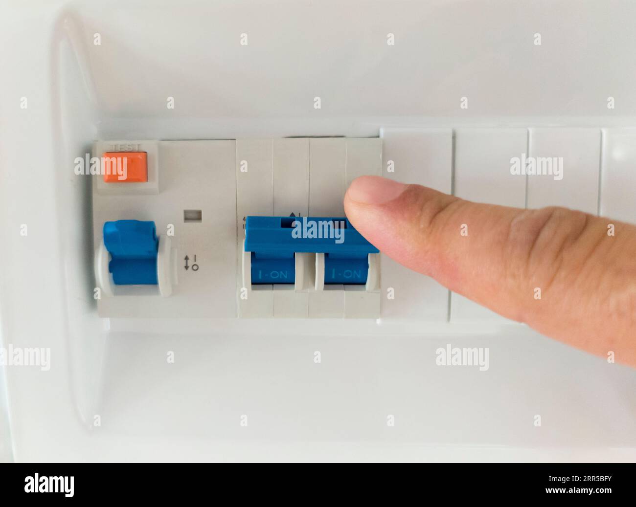 Finger pressing the lever of residual current operated circuit breaker ...