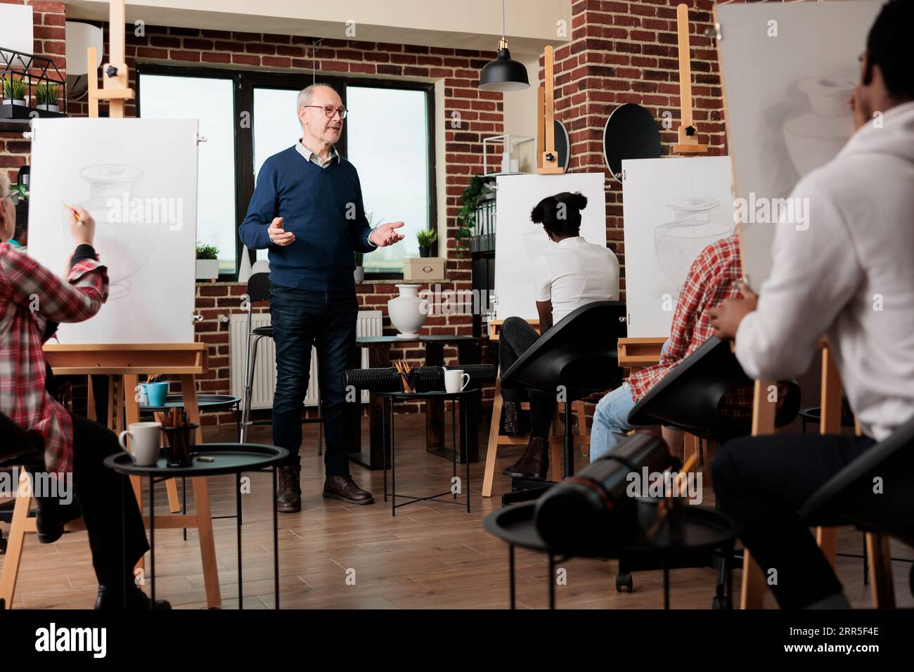 Senior man experienced artist teaching drawing classes to adults ...