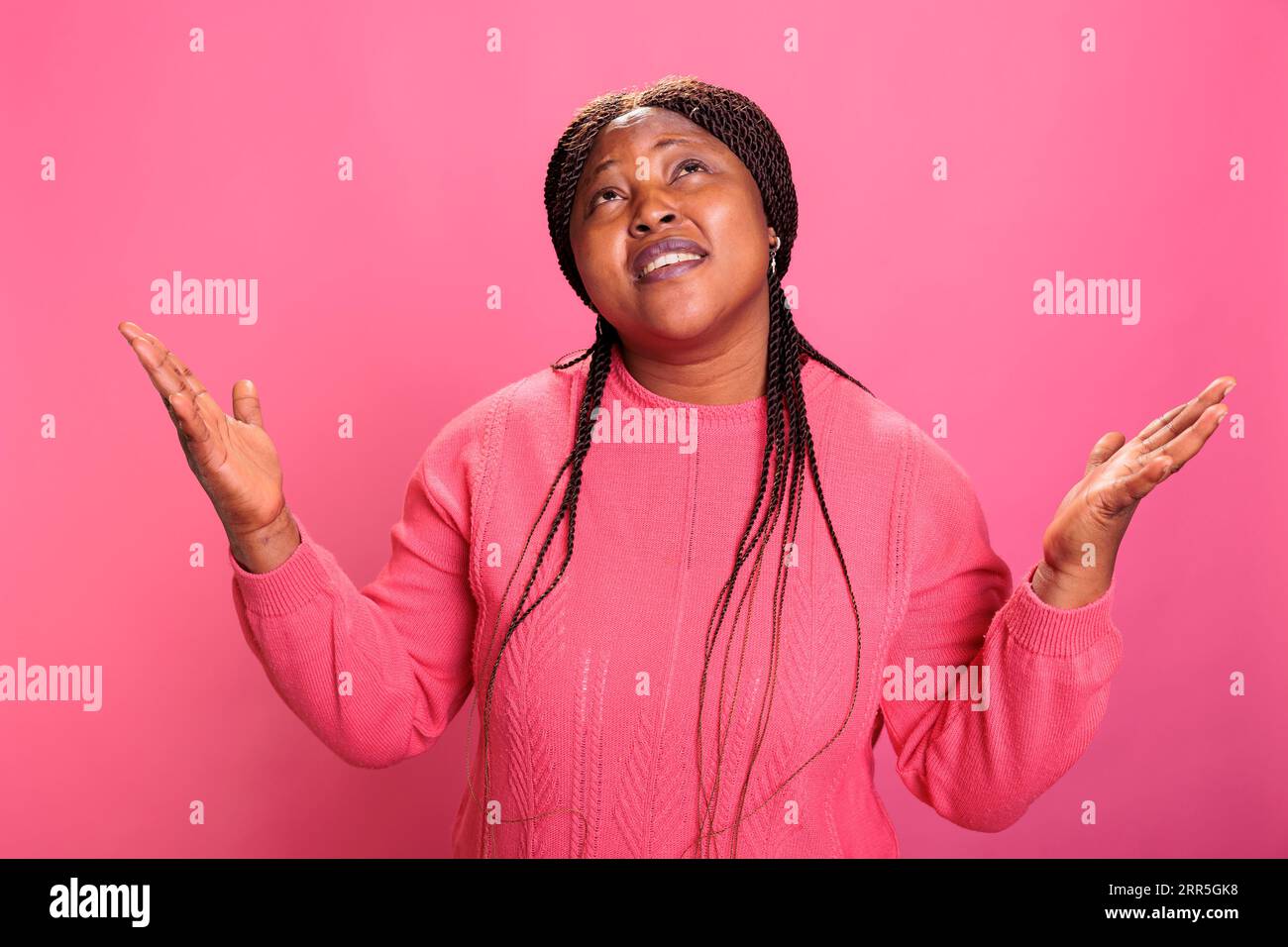 Faithful catholic woman in pink sweather standing with palms faced to ...