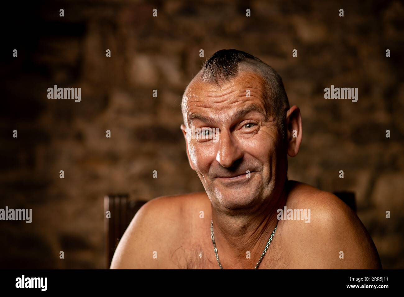 A satisfied older man, sixty years old, smiles and looks at the camera ...