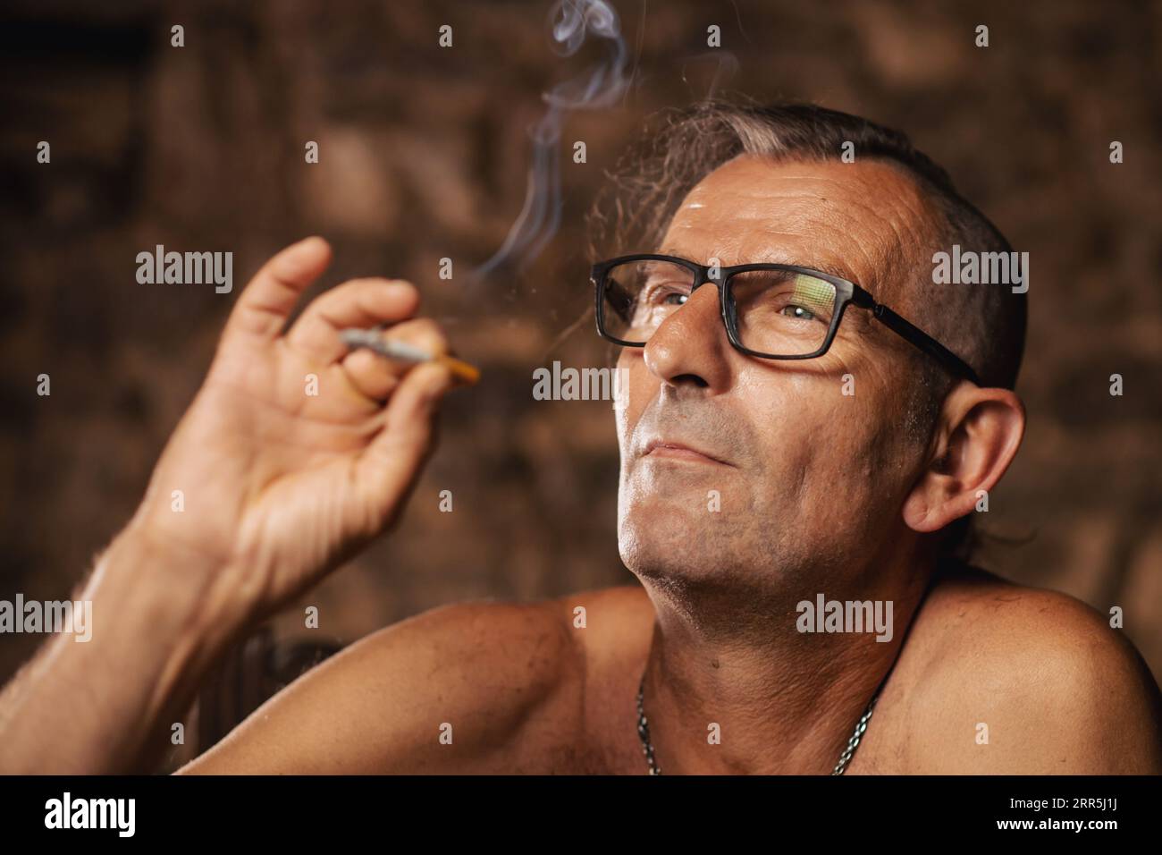 A satisfied older man, sixty years old, smokes thoughtfully Stock Photo ...