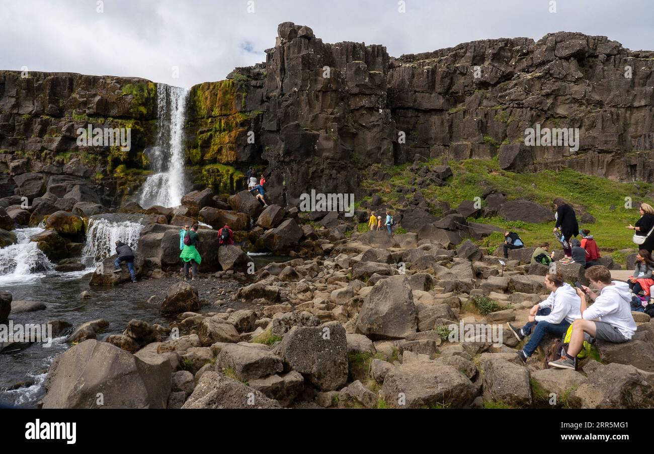 Tourists visit the waterfall Öxaráfoss (The waterfall in the Ax River ...