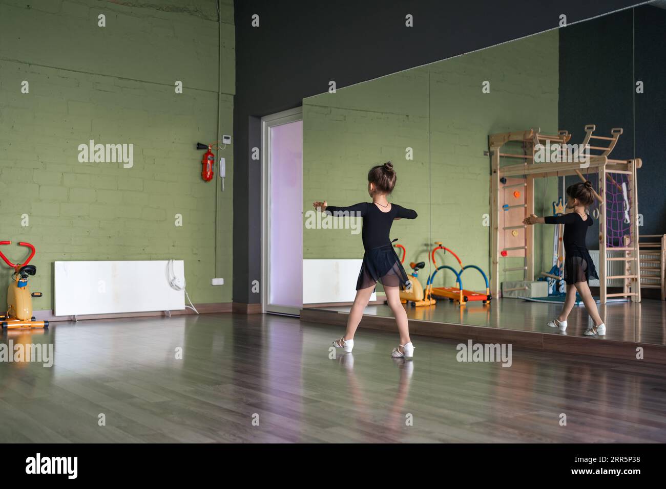 Child girl standing in black sport bodysuit in dancing studio during ...