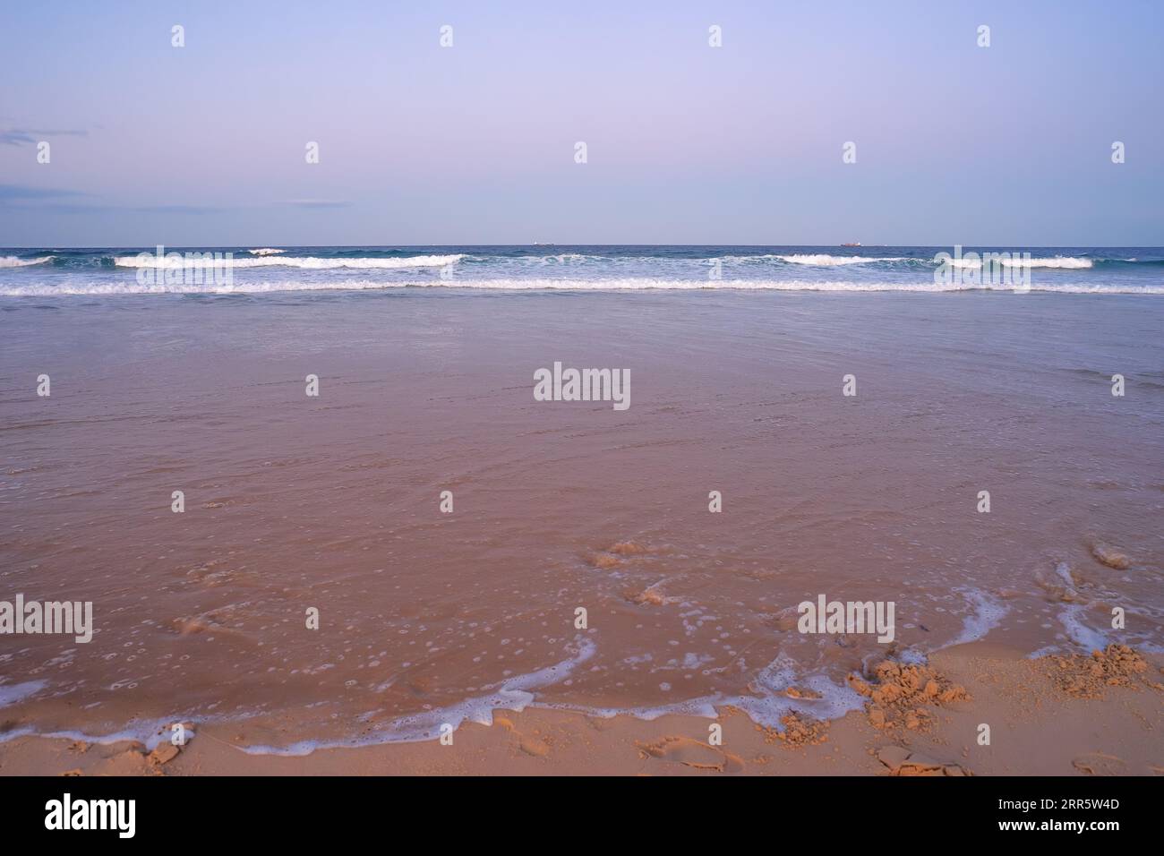 The foreshore covered by water as the tide rises on a sandy surf beach ...