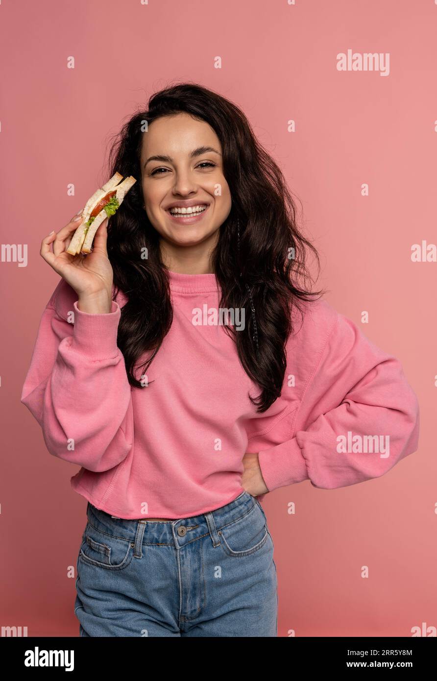 Cheerful attractive brunette posing for the camera on the pink ...