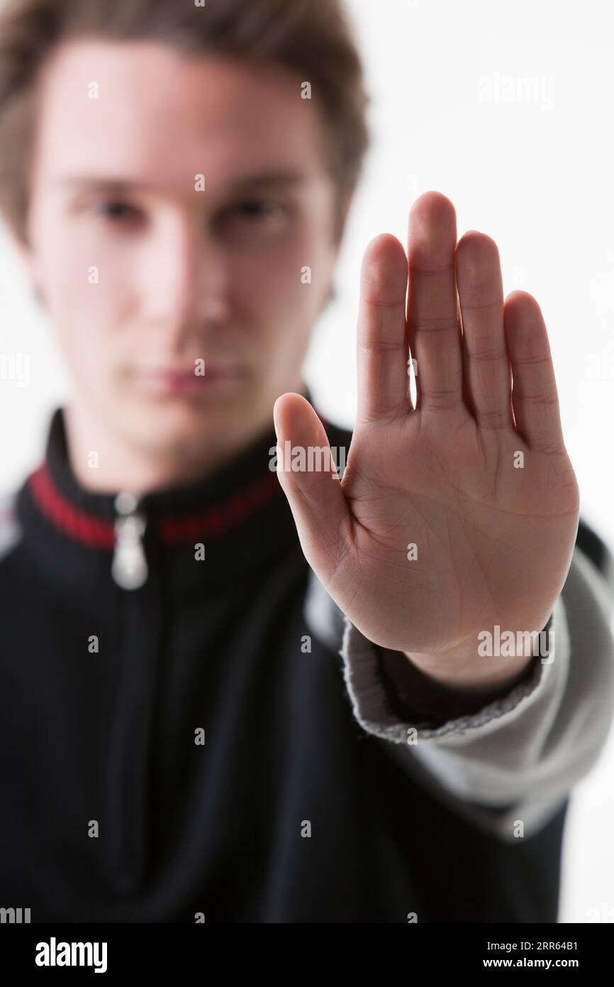 determined young man raises his hand signaling 'stop." He's taking a ...