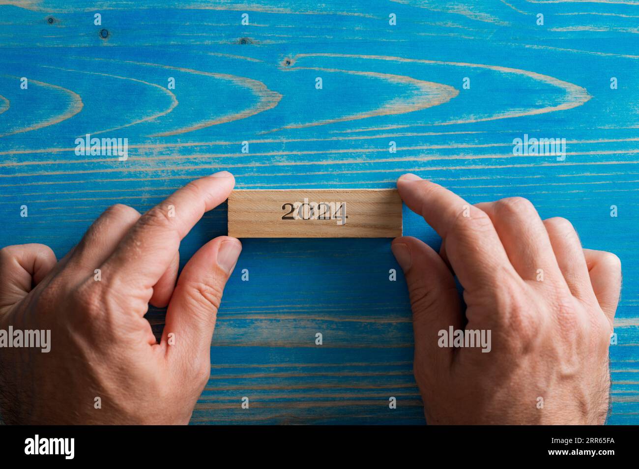 Overhead view of male hands placing wooden tag with 2024 sign on it ...
