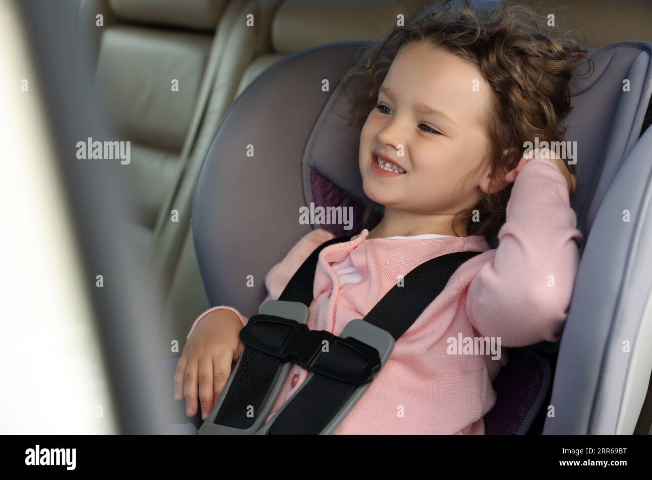 Cute little girl sitting in child safety seat inside car Stock Photo ...