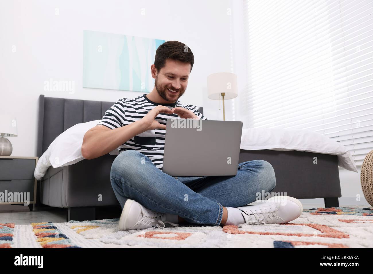 Happy man making heart with hands during video chat via laptop in ...