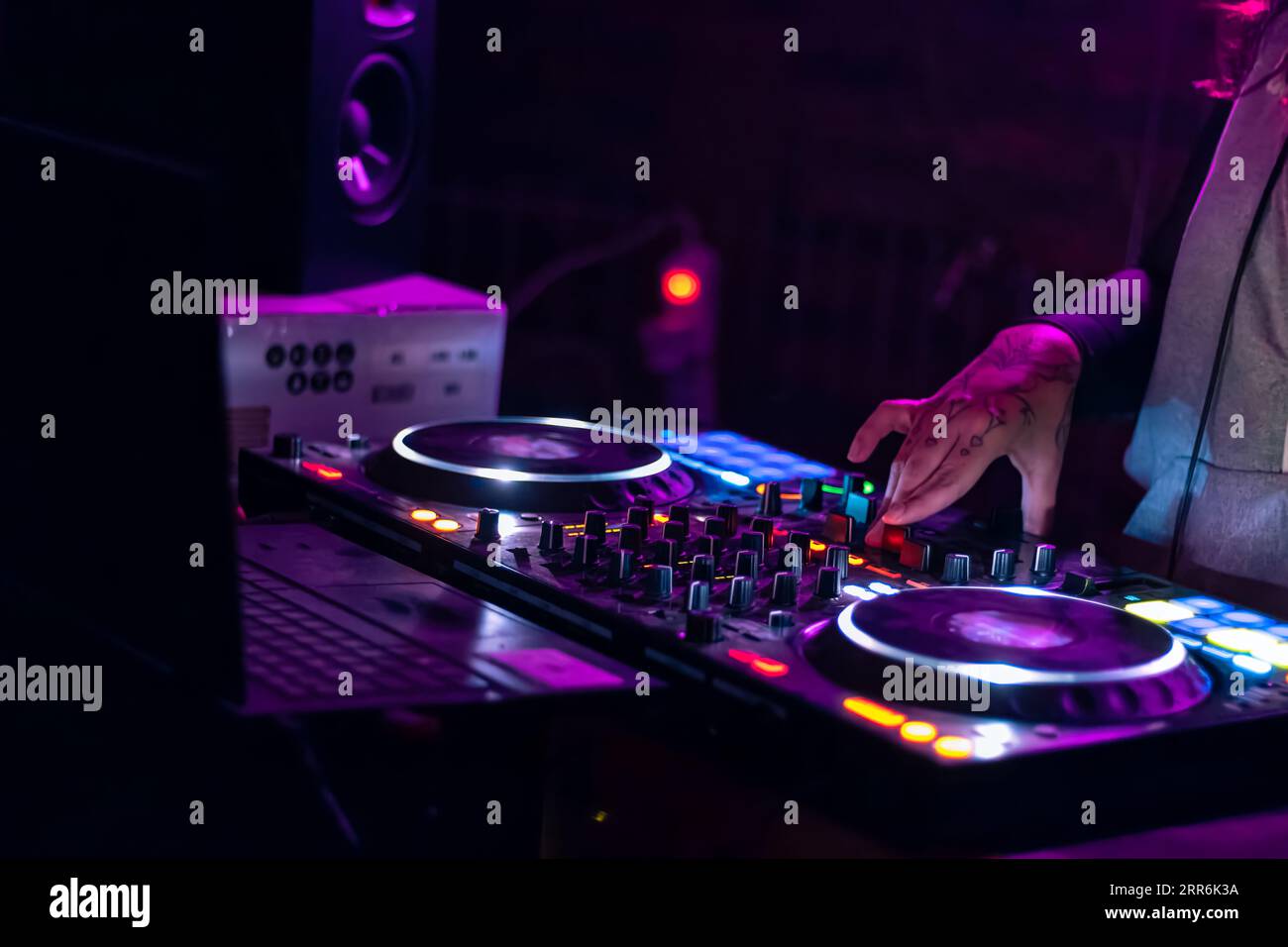 hands of dj playing at an electronic party with colored lights and ...