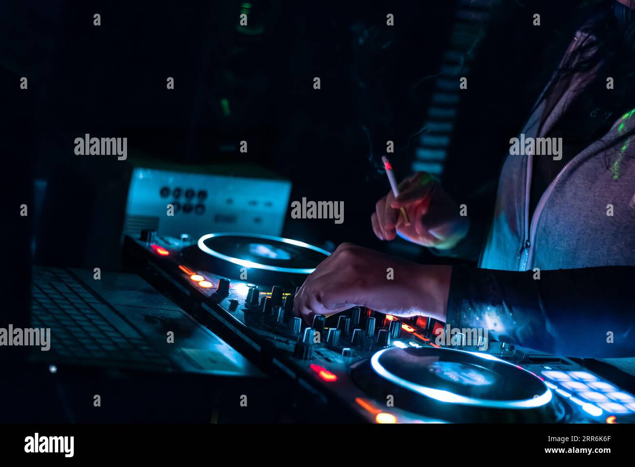 hands of dj playing at an electronic party with colored lights and ...