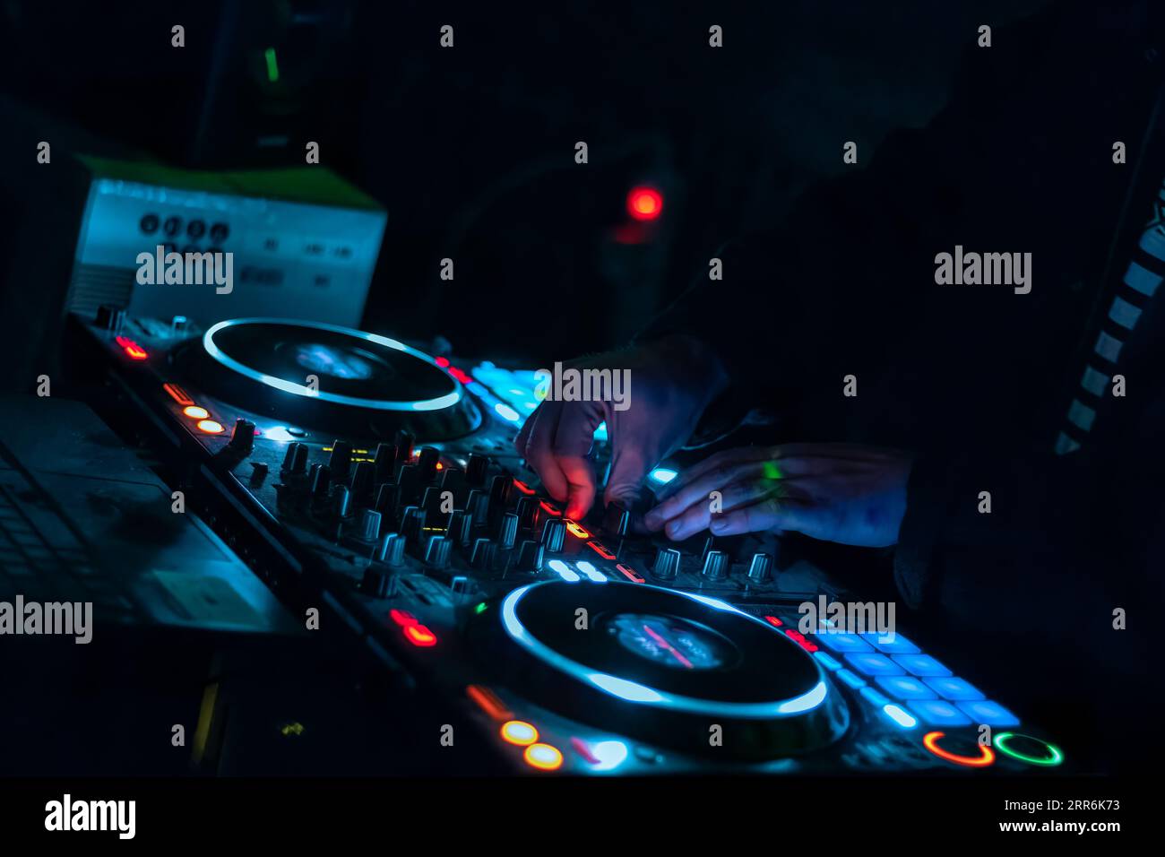 Close up of DJ hands playing various track controls on the DJ mixing ...