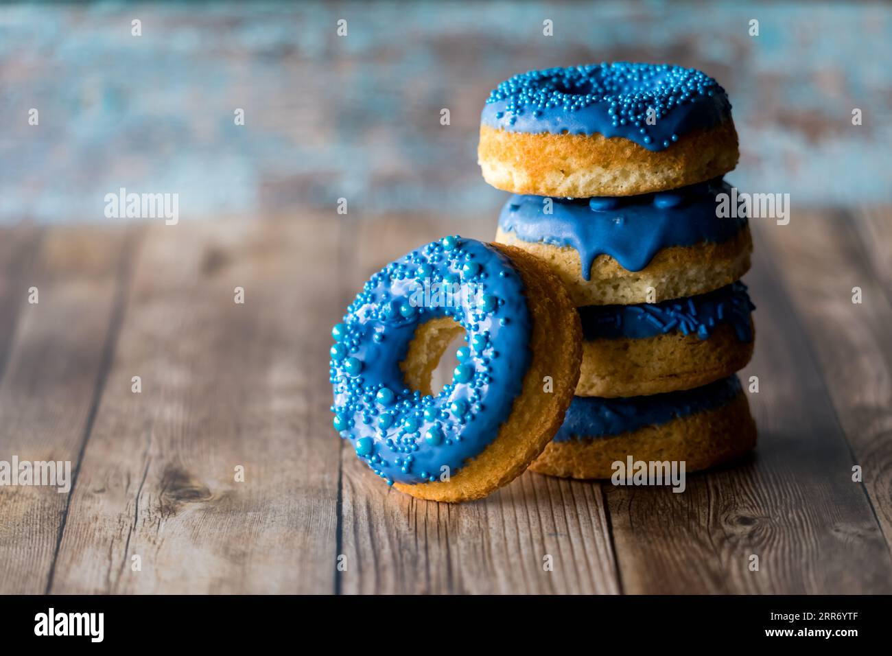A stack of blue decorated donuts with one leaning in front Stock Photo ...