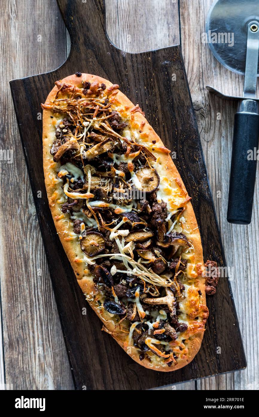 Top down view of a mushroom beef flatbread pizza ready for slicing ...