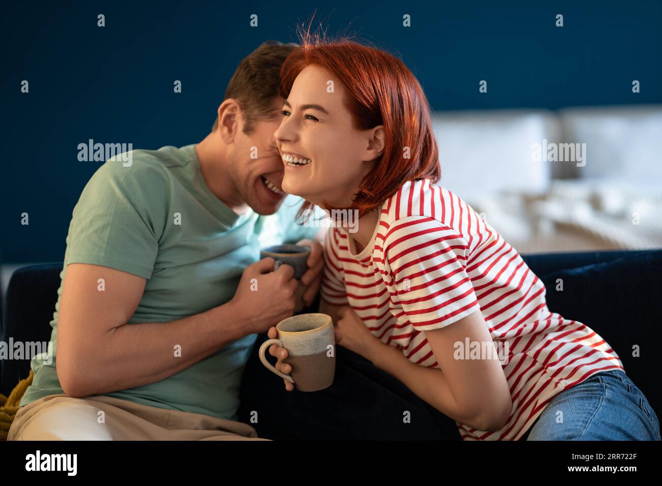 Well rested couple talking laughing and joking sitting on home sofa ...