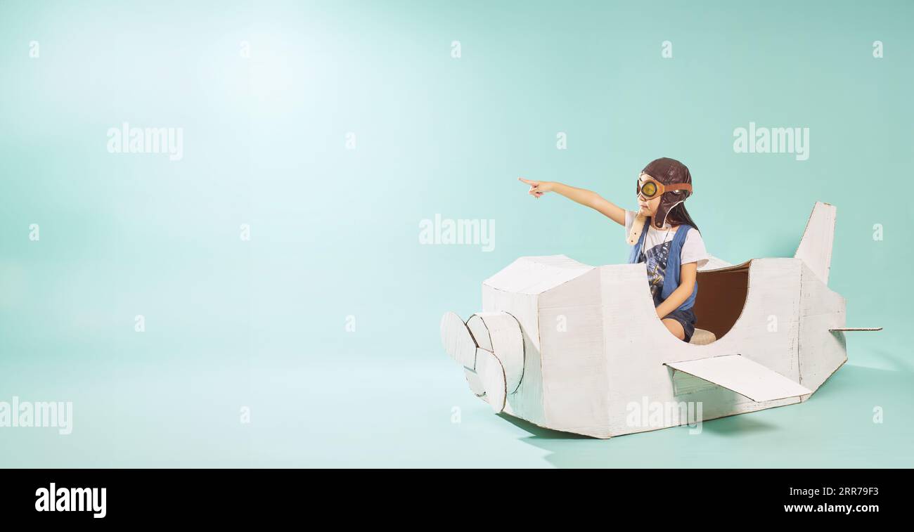Little cute girl playing with a cardboard airplane. White retro style ...