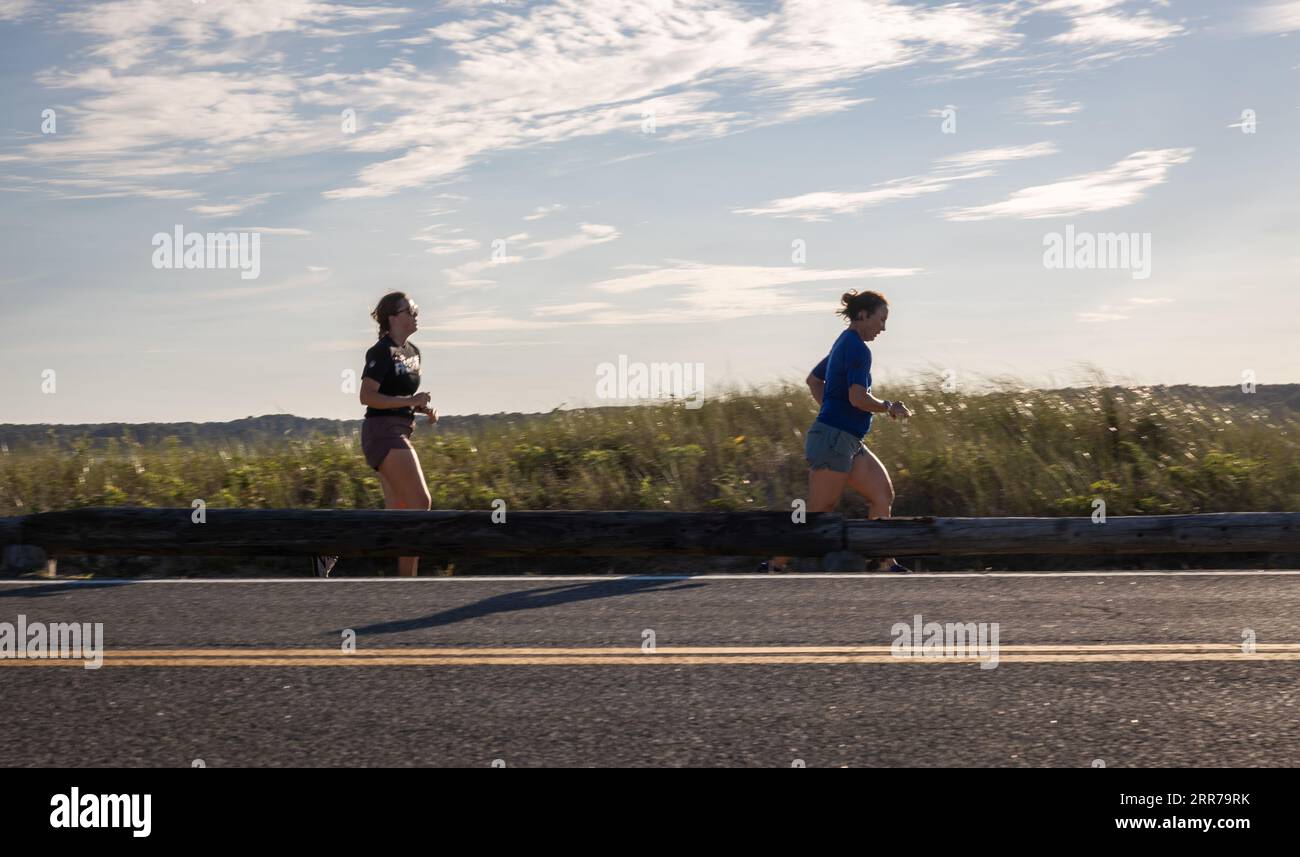 A group of people running along the shoreline of Martha's Vineyard on a ...