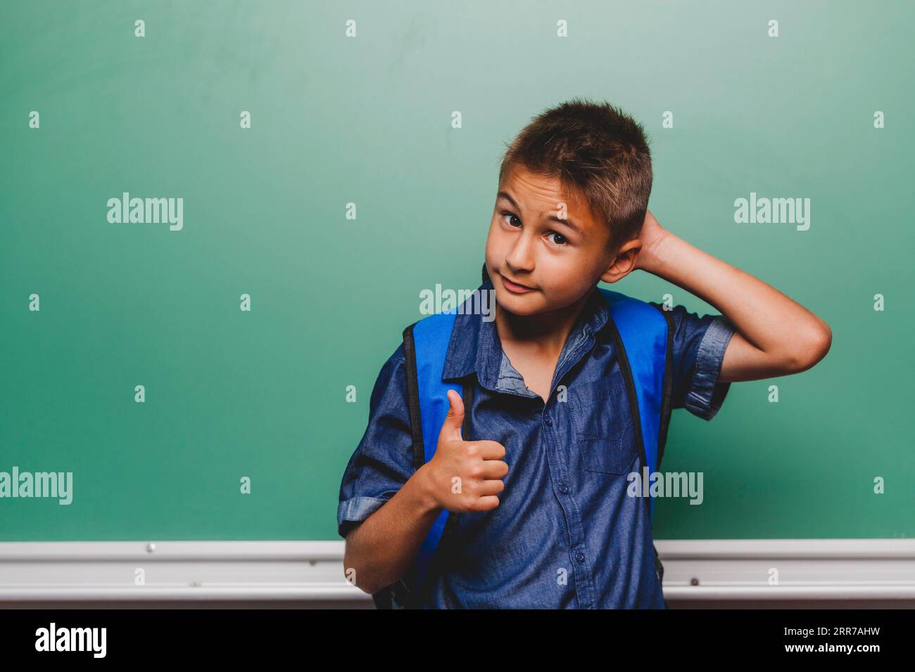 Boy scratching head gesturing thumb up Stock Photo - Alamy