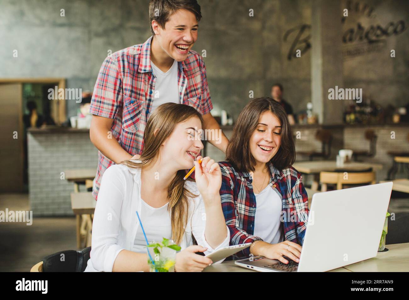 Cheerful students posing with laptop Stock Photo - Alamy
