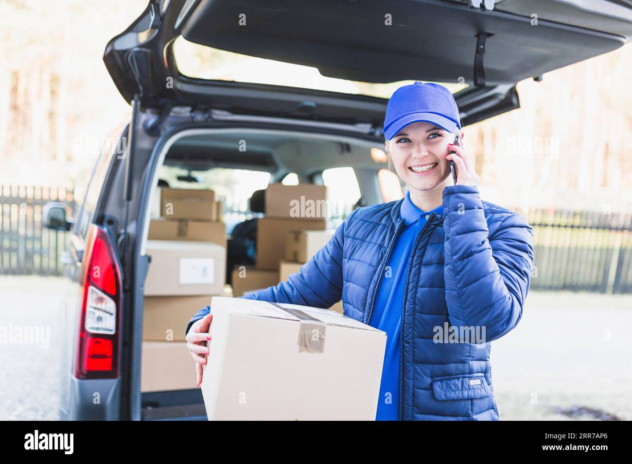 Charming delivery girl having phone call Stock Photo - Alamy