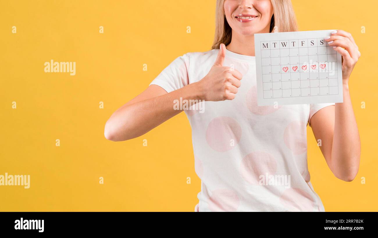 Medium shot woman showing her period calendar thumps up Stock Photo - Alamy