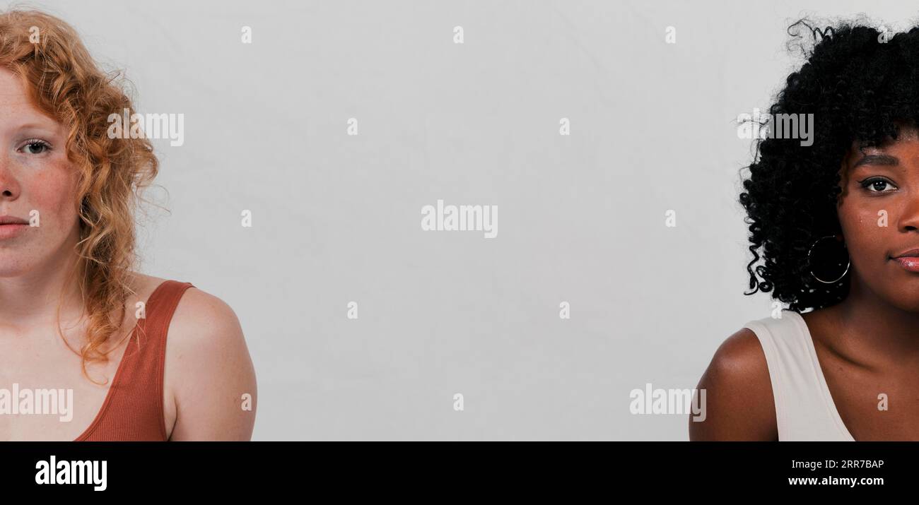 Panoramic view blonde black young women looking camera against grey ...