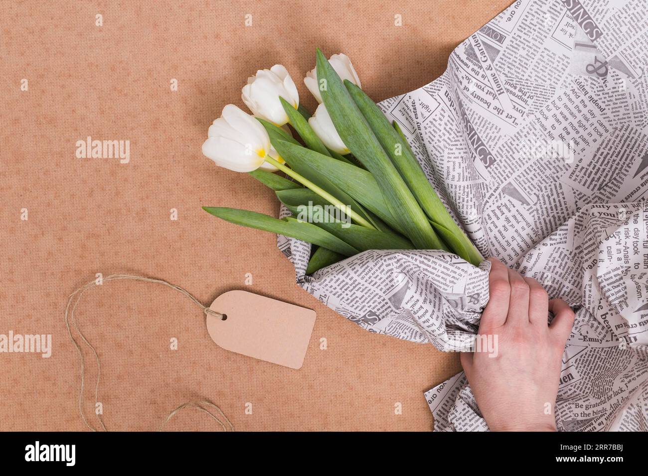 Person s hand wrapping white tulip flowers newspaper with price tag ...