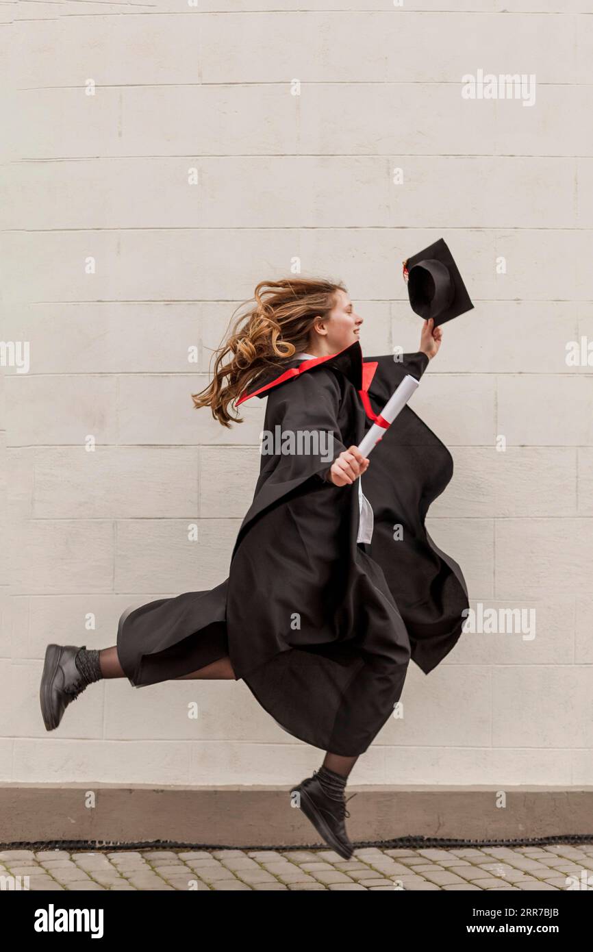 Side view girl jumping graduation Stock Photo - Alamy