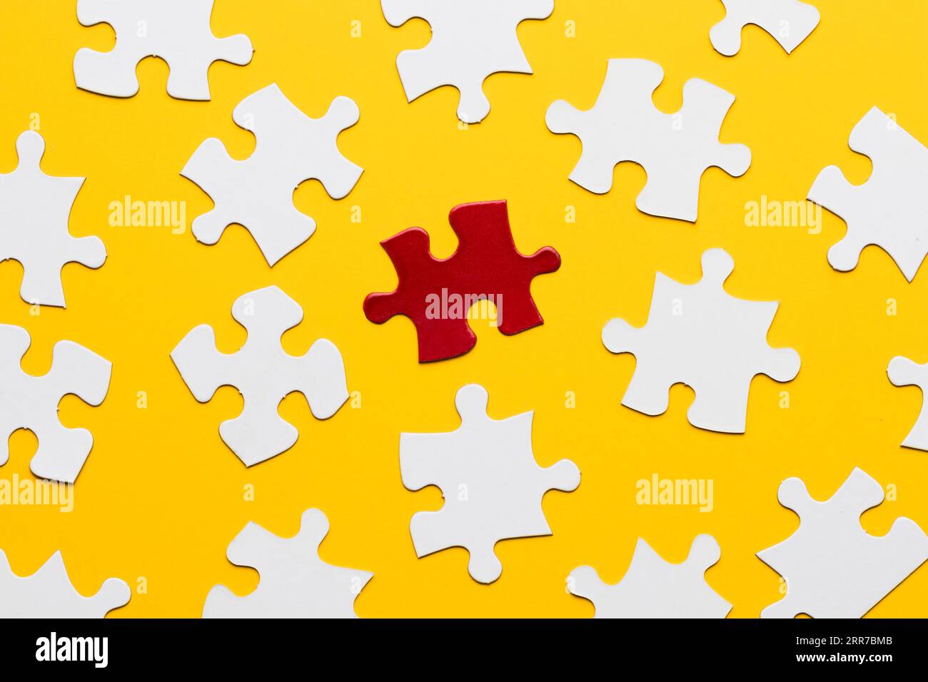 Red bright puzzle among white against yellow backdrop Stock Photo - Alamy