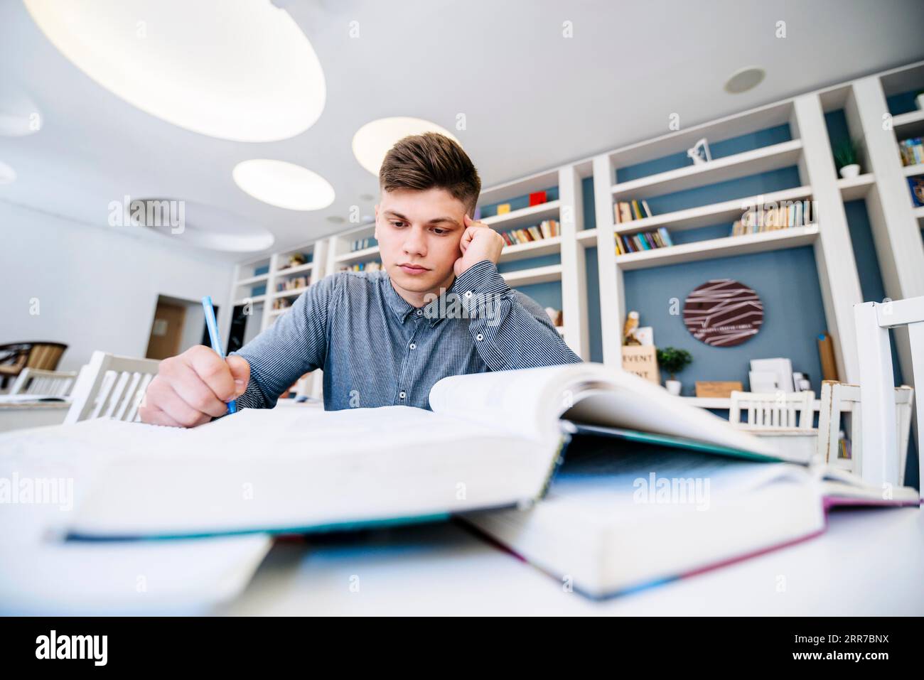 Student reading with books table library Stock Photo - Alamy